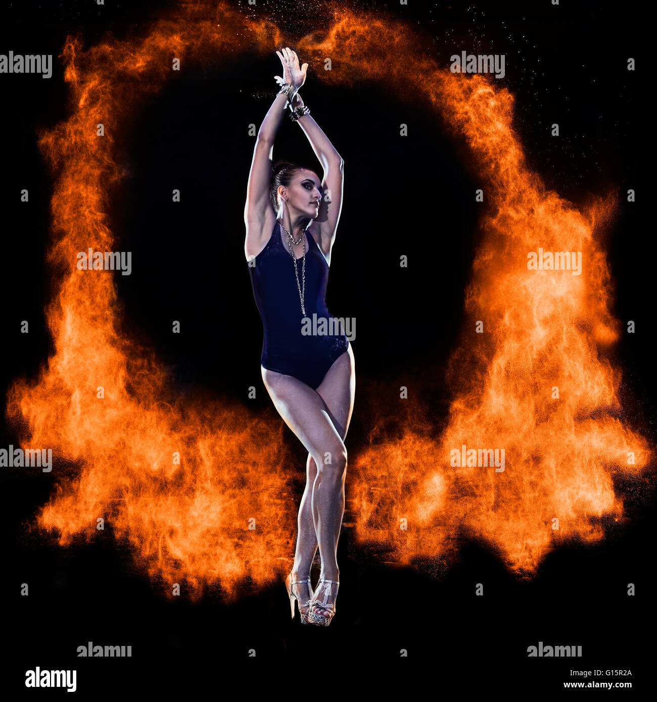 Young woman jumping in fire red powder cloud on black background Stock ...