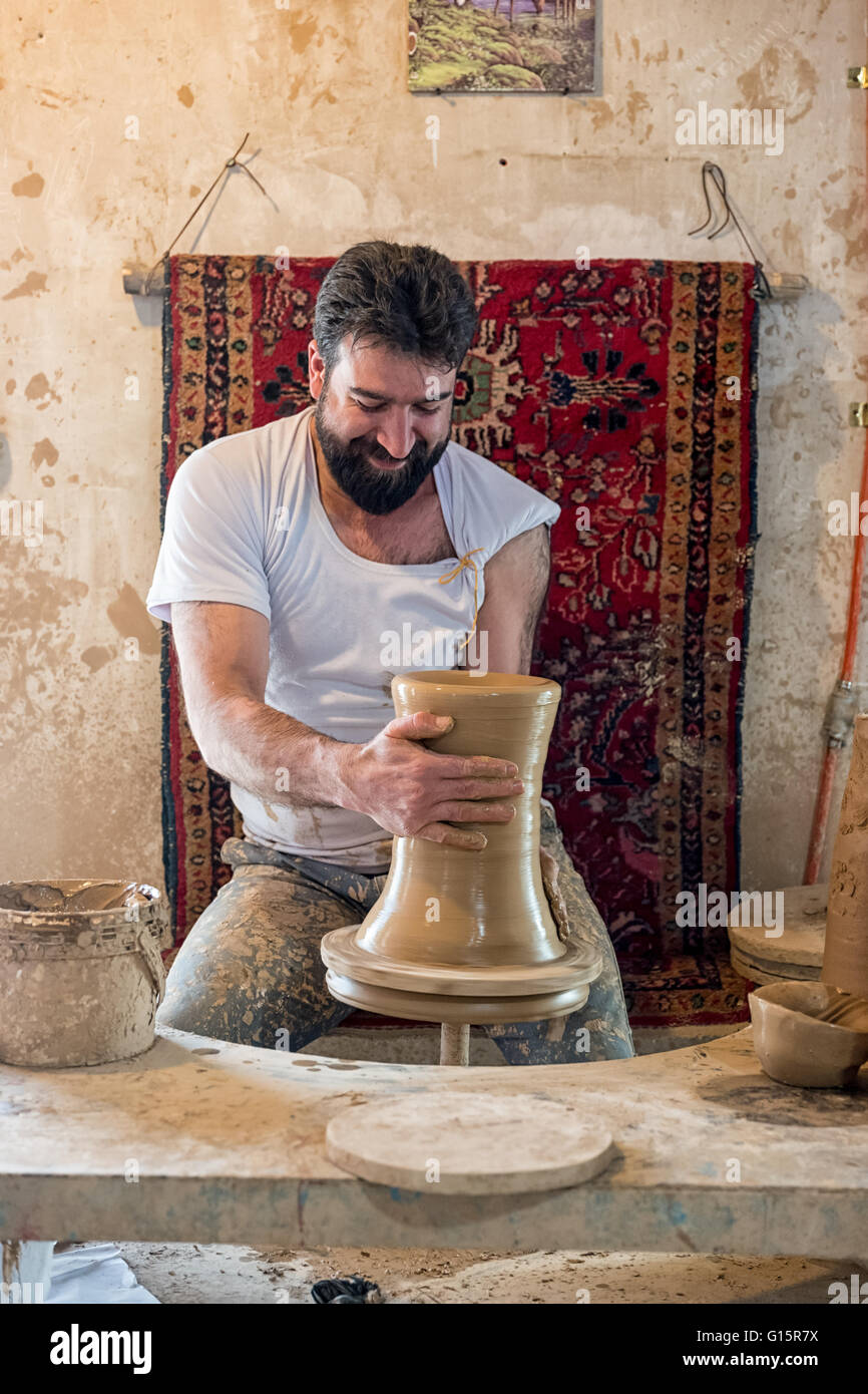 Iradj Naderi uses a potter's wheel to shape a large vase made of clay ...