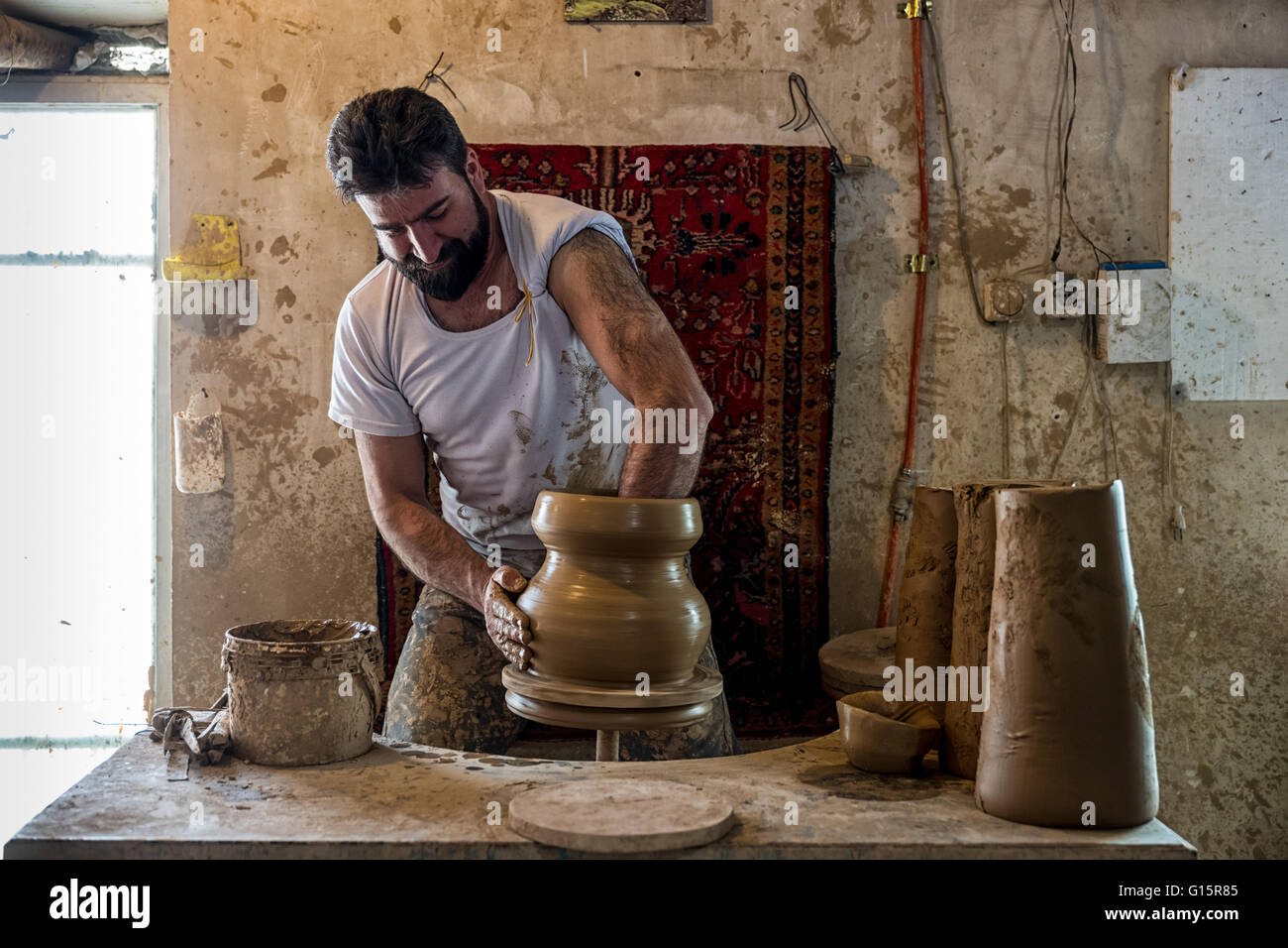 Iradj Naderi uses a potters wheel to shape a large pot made of clay in ...
