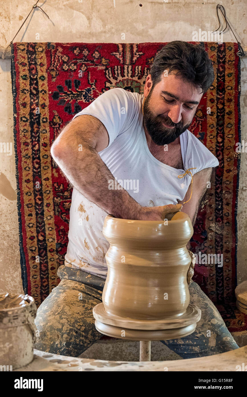 Iradj Naderi uses a potters wheel to shape a large pot made of clay in ...