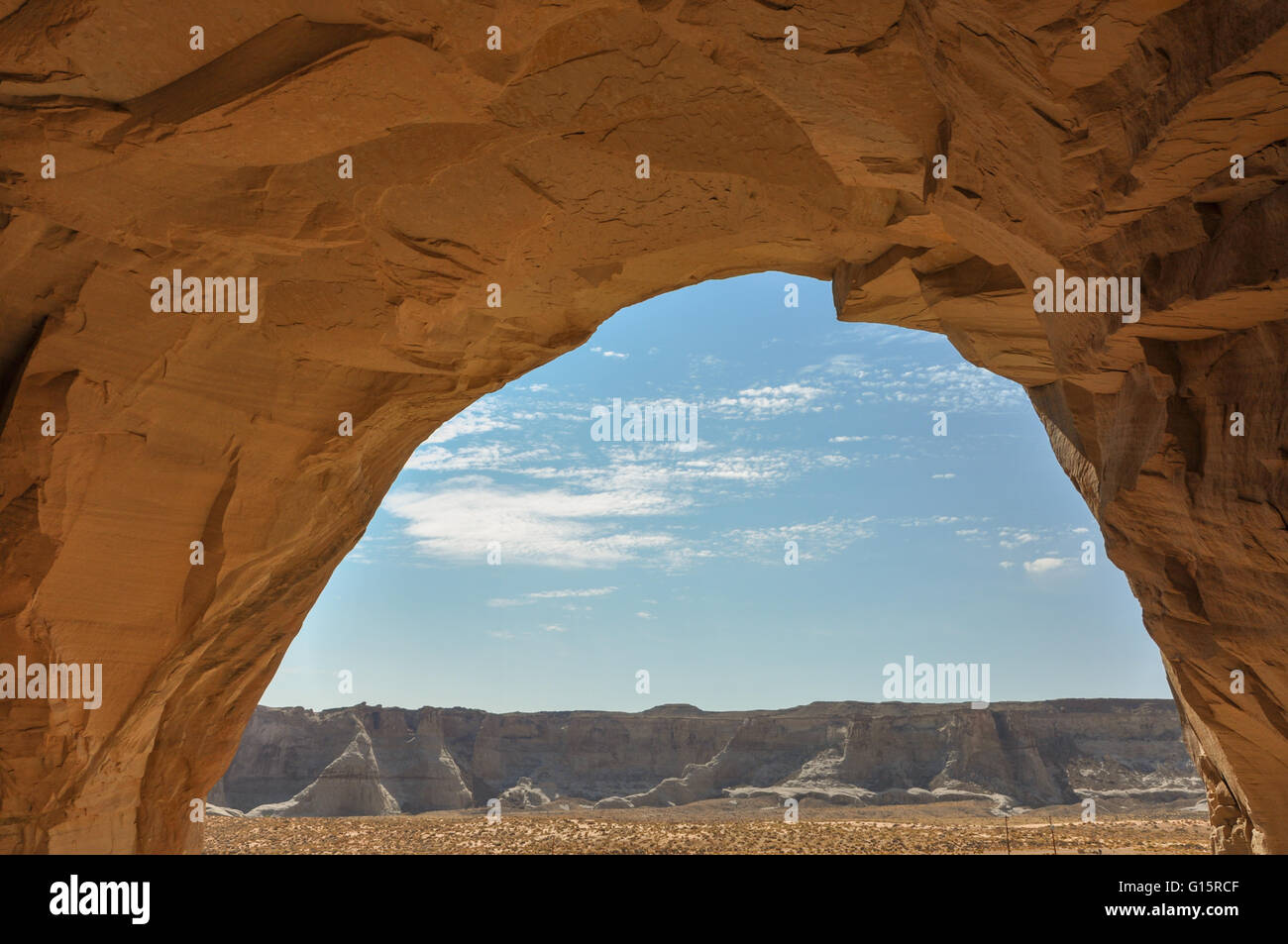 stone arch in Southeast UT desert with distant mountain range and sky ...