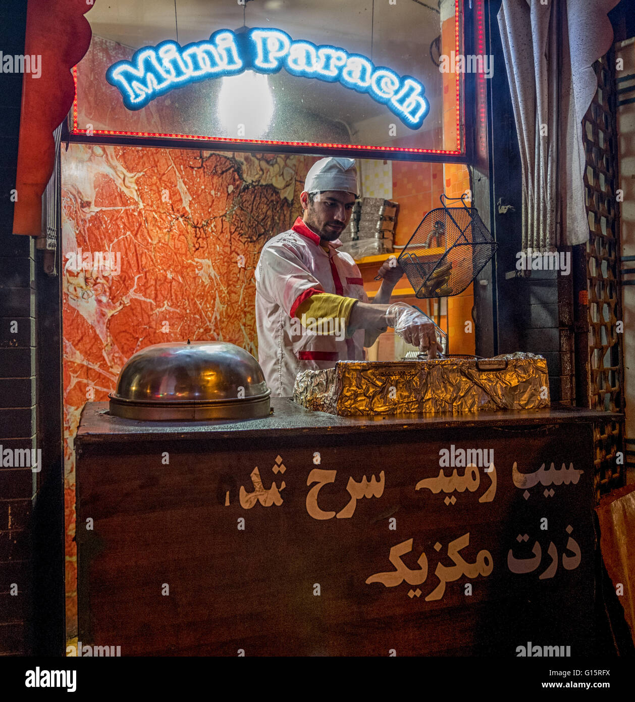 Iranian man in a chef's hat cooking and selling fried food from a ...