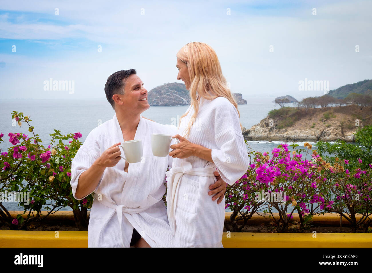 Caucasian couple in white bath robes having coffee on the terrace of an ...