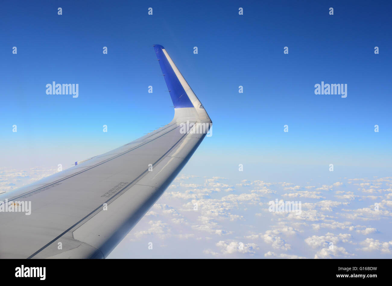 View of the airplane wing and beautiful blue cloudy sky though an ...