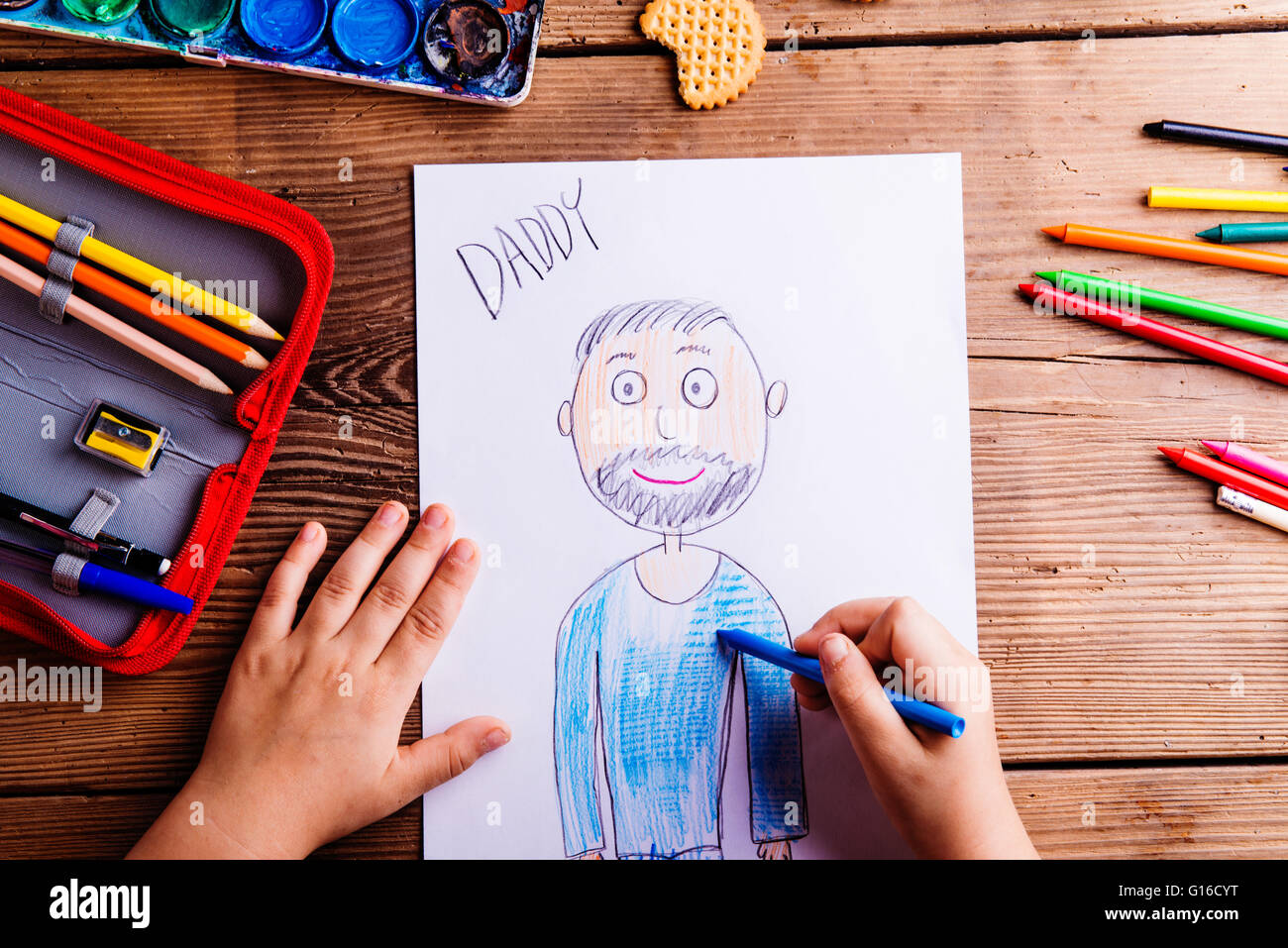 Unrecognizable girl drawing picture of her father. Wooden backgr Stock ...