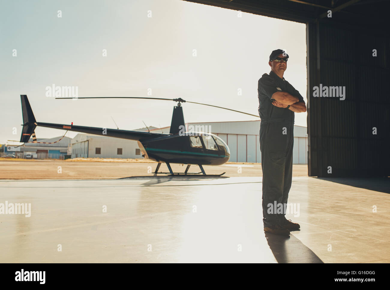 Full length portrait of confident pilot standing with his arms crossed ...