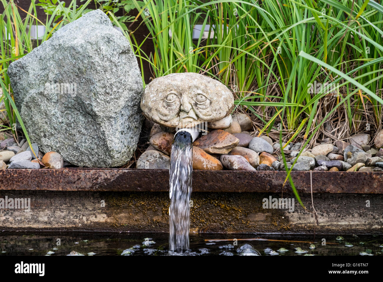 Sad stone face water feature Stock Photo - Alamy