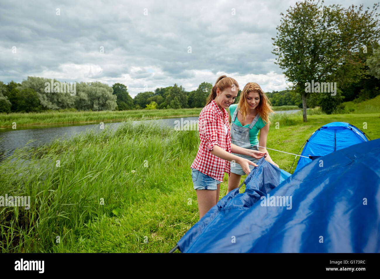 smiling friends setting up tent outdoors Stock Photo - Alamy
