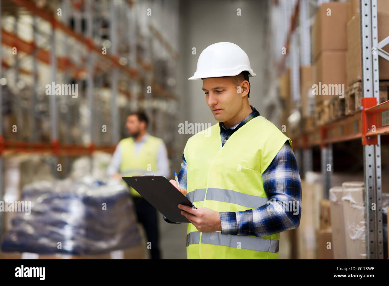 man with clipboard in safety vest at warehouse Stock Photo - Alamy