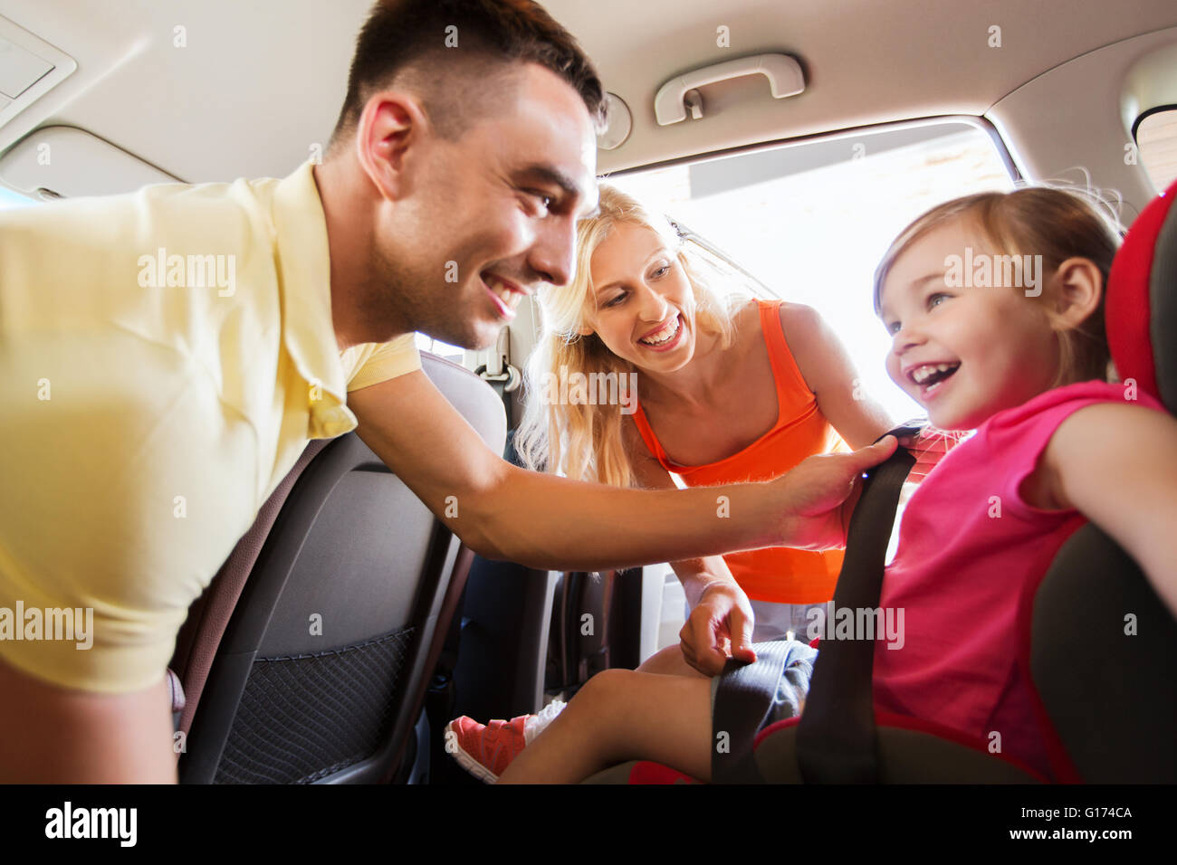 happy parents fastening child with car seat belt Stock Photo - Alamy