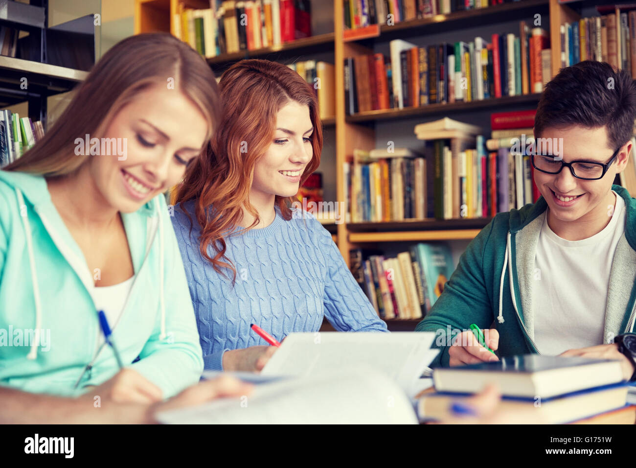 happy students writing to notebooks in library Stock Photo - Alamy