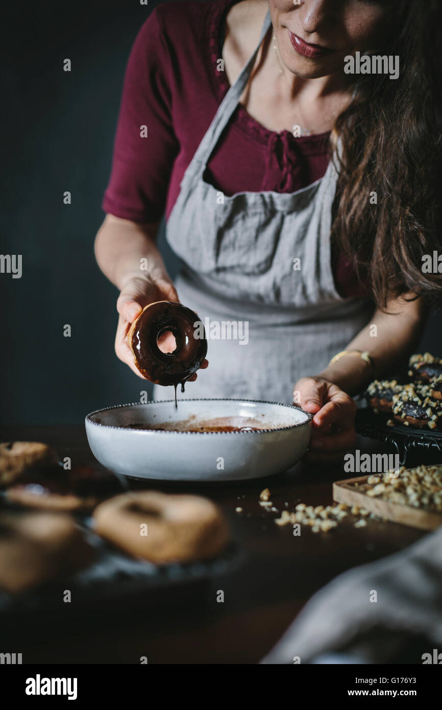 A woman is dipping donuts in chocolate glaze Stock Photo - Alamy