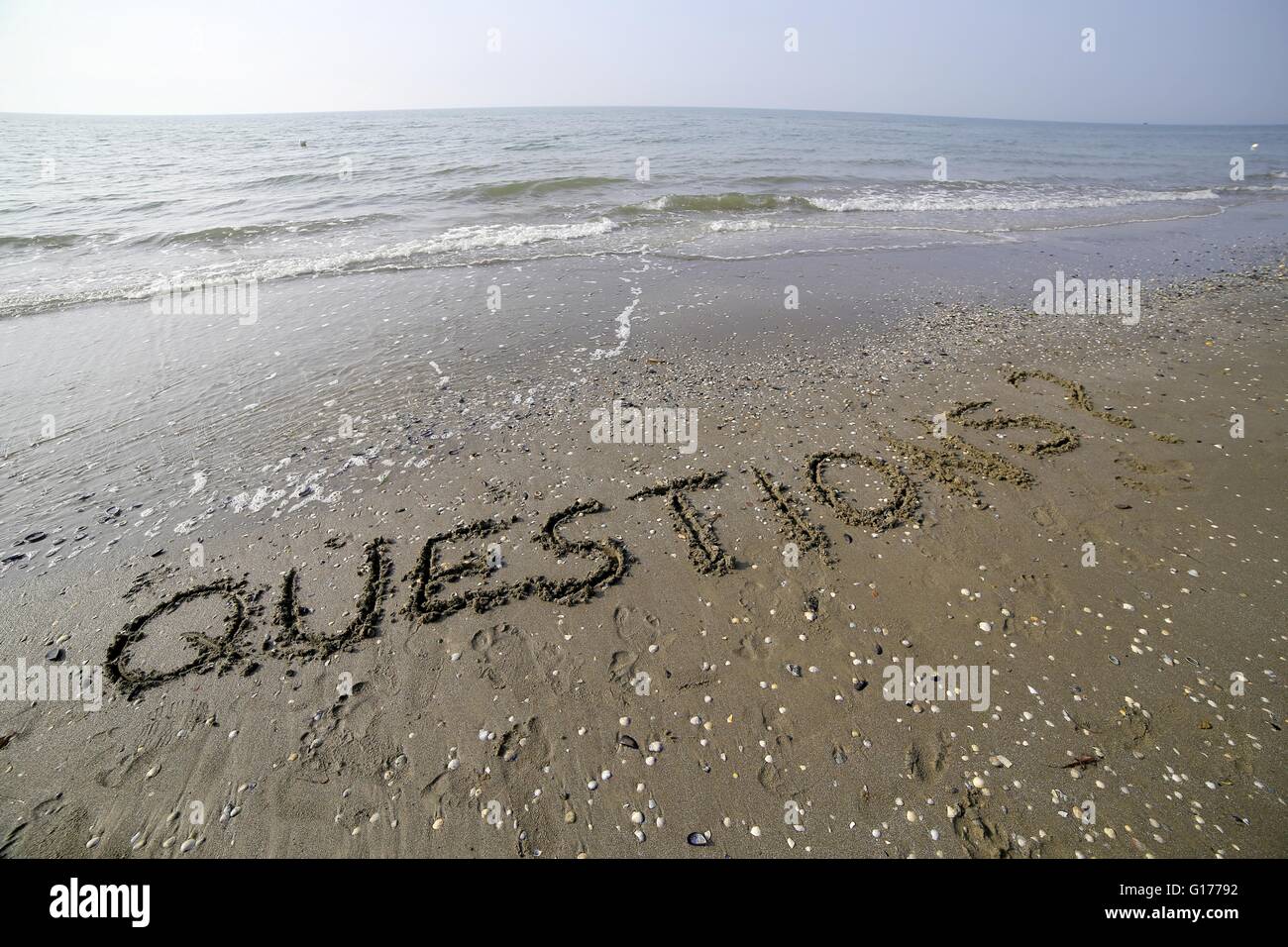 QUESTIONS with question mark written in large letters on the sand of ...