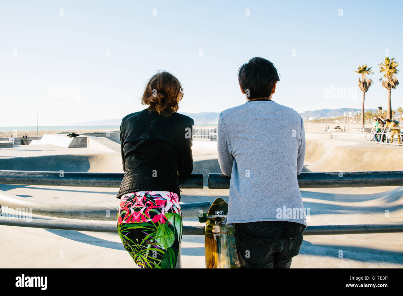 Young couple standing together, leaning on railings, rear view Stock ...