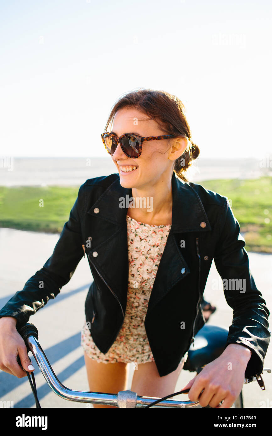 Young woman leaning on bicycle handlebars at coast, Venice Beach ...