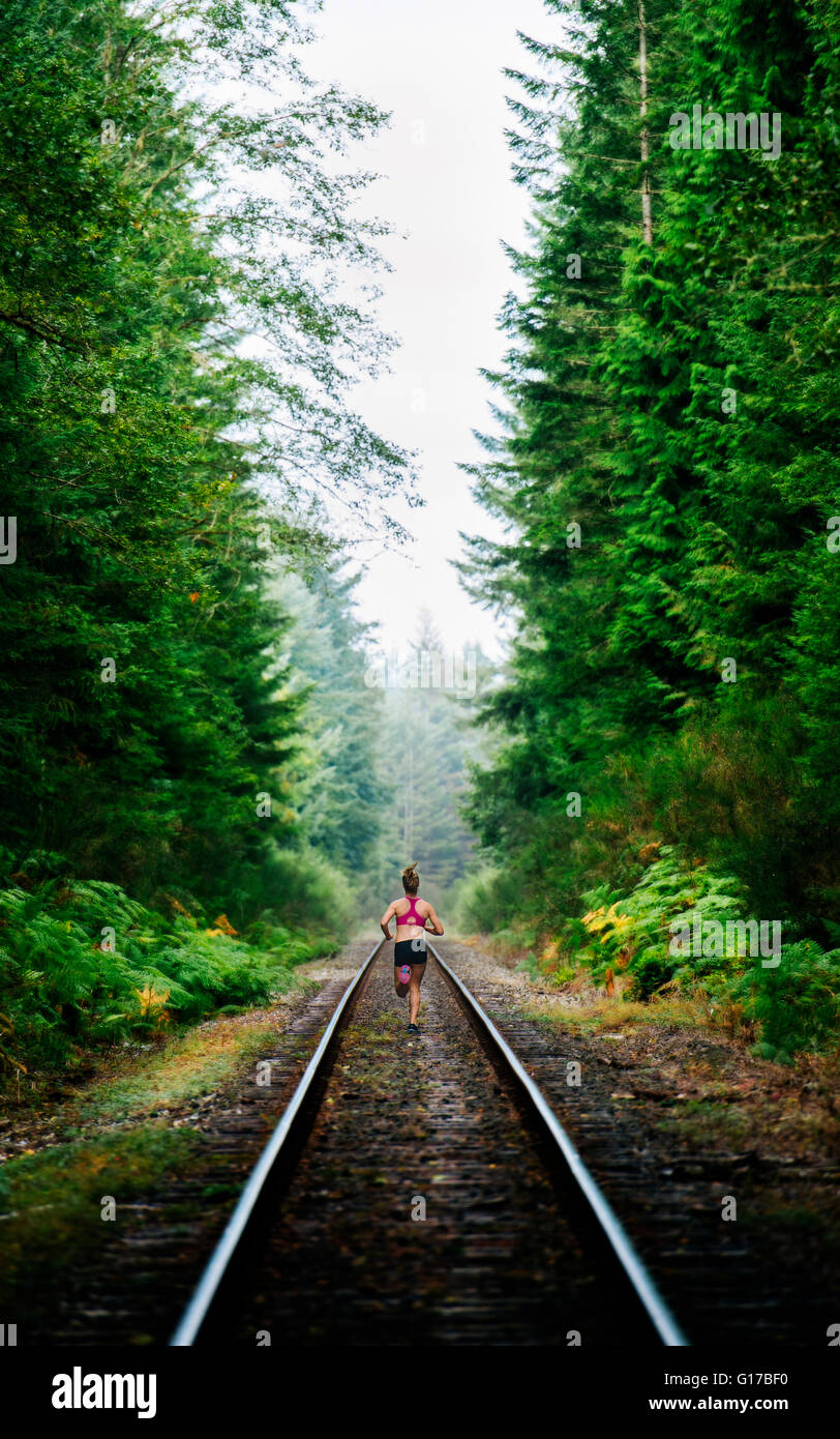 Young woman running along rural train track, rear view Stock Photo - Alamy