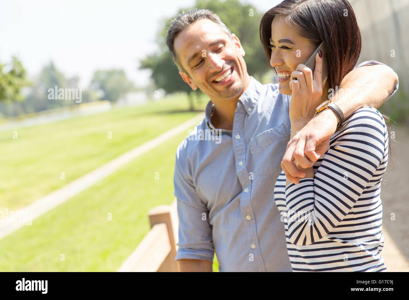 Couple using smartphone to make telephone call smiling Stock Photo - Alamy