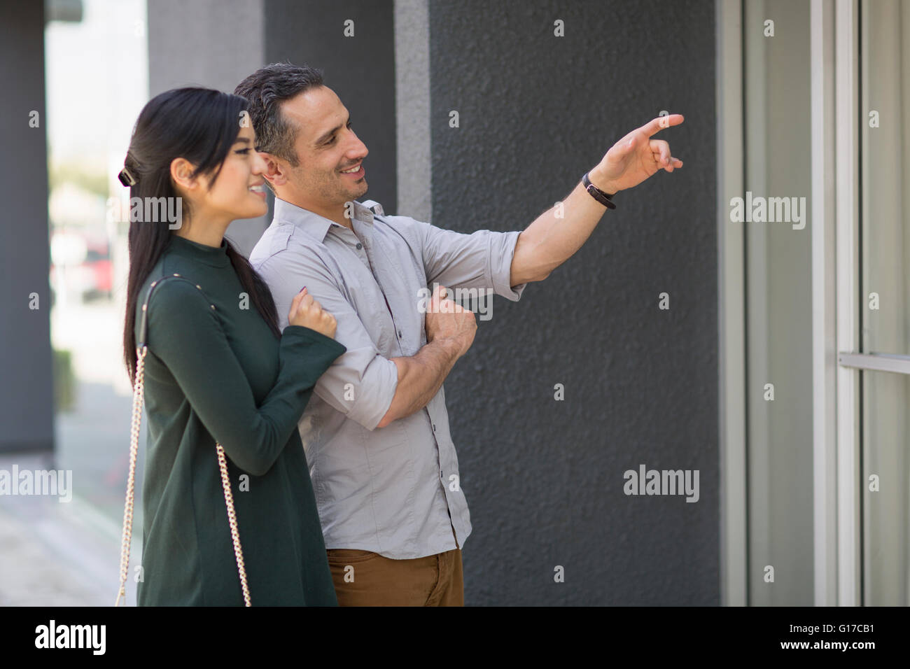 Couple window shopping pointing and smiling Stock Photo - Alamy