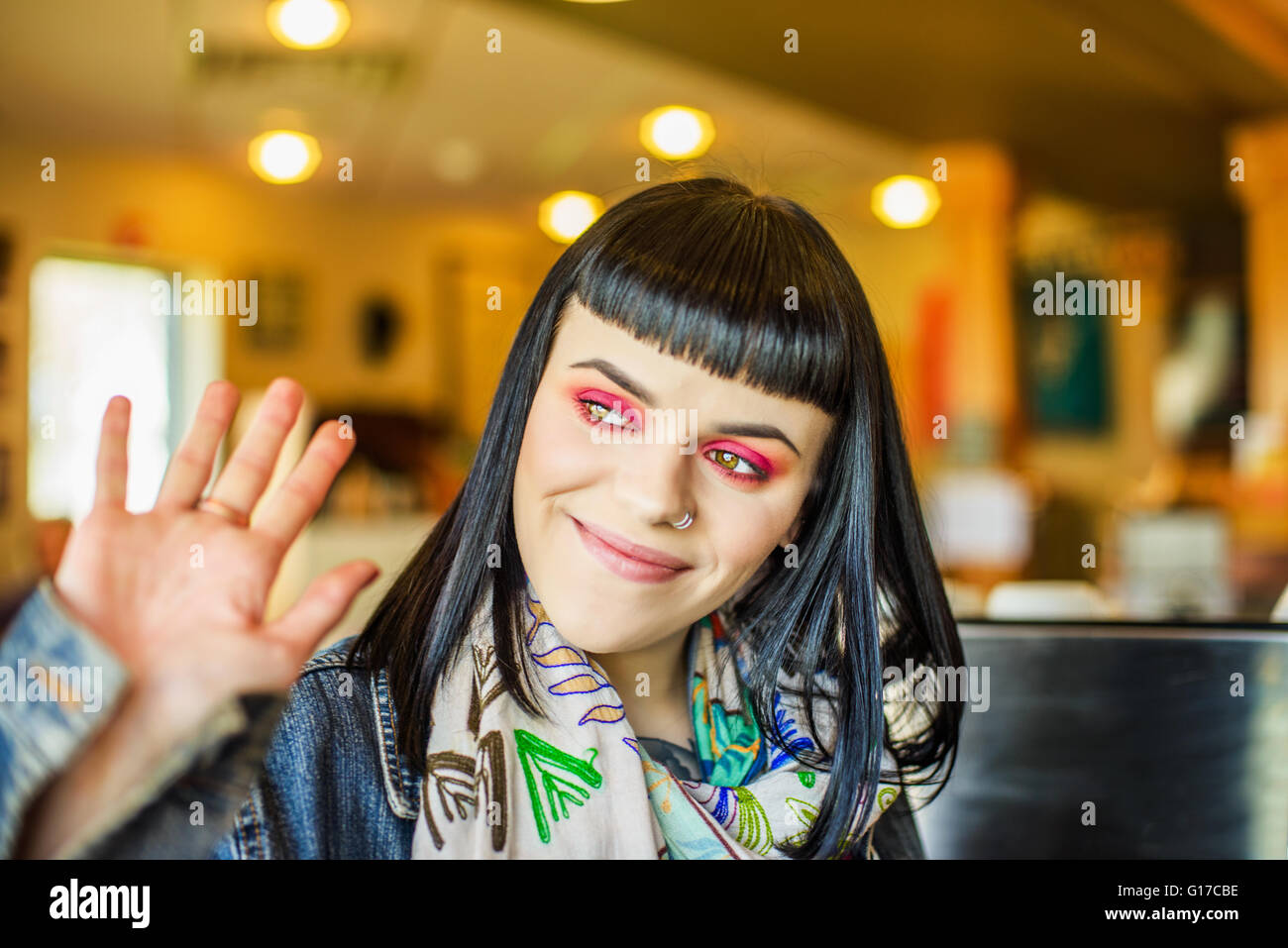 Woman waving, looking away smiling Stock Photo - Alamy