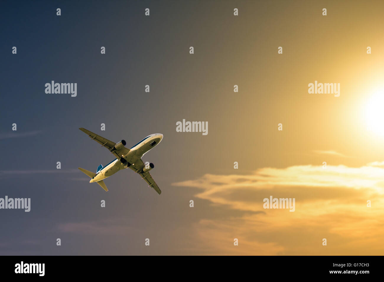 A plane flying towards a beautiful sunset Stock Photo - Alamy