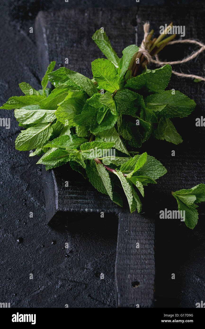 Bunch of fresh mint with thread on black wooden chopping board over ...