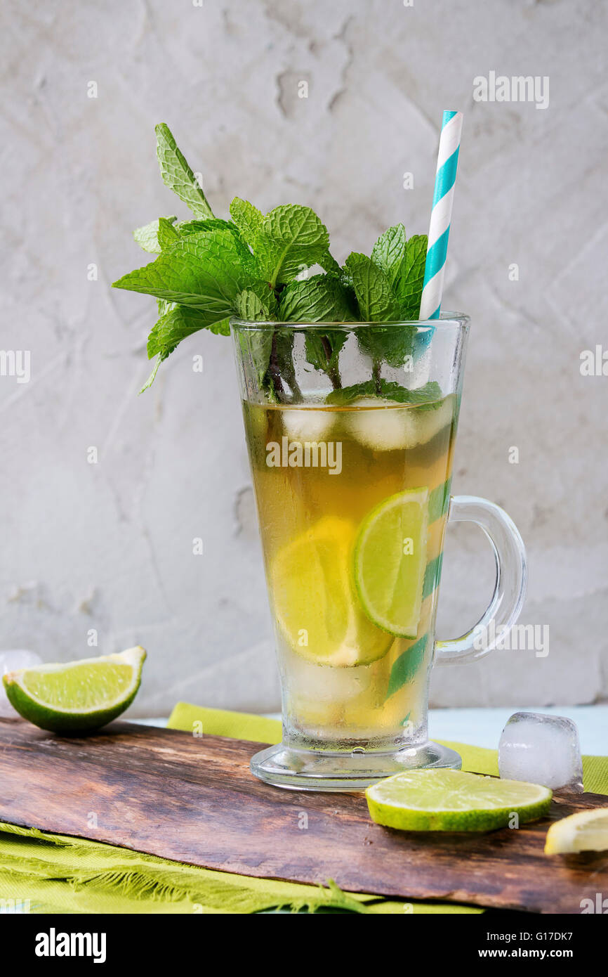 Glass of Iced green tea with lime, lemon, mint and ice cubes on wooden ...