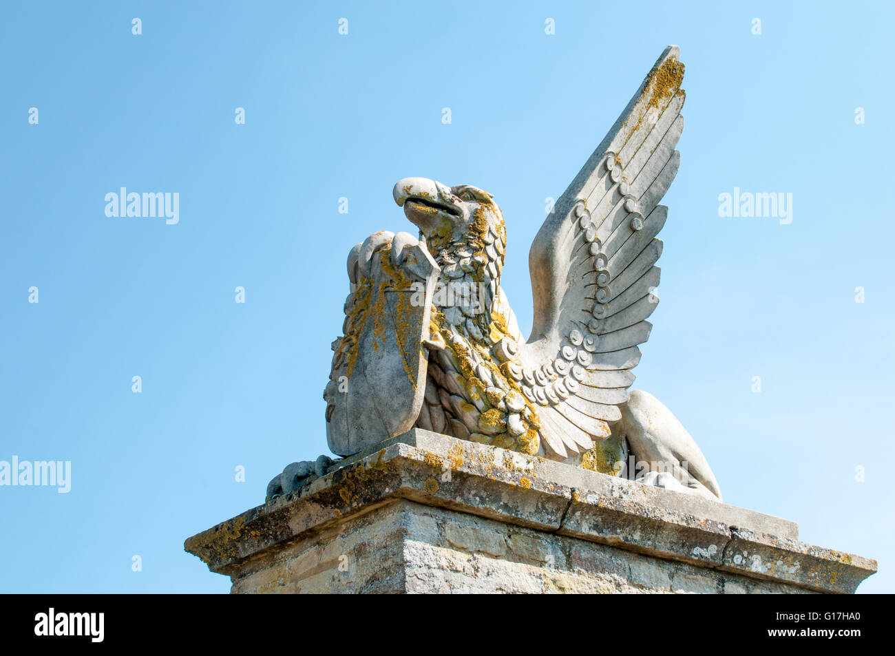 Statue of a winged mythical creature on a plinth holding a shield Stock ...