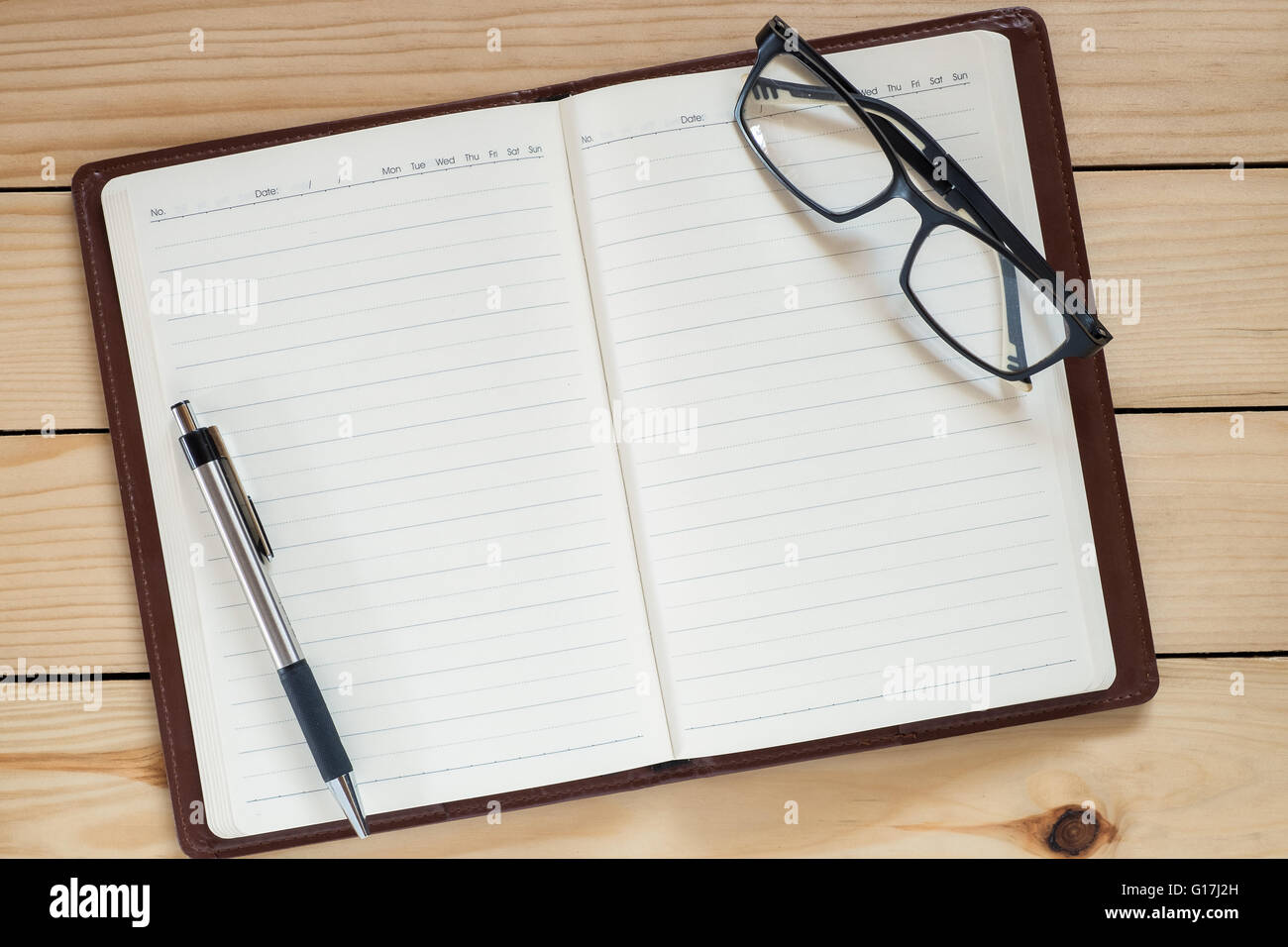 Office workplace with notebook, eye glasses and pen on rustic wood ...