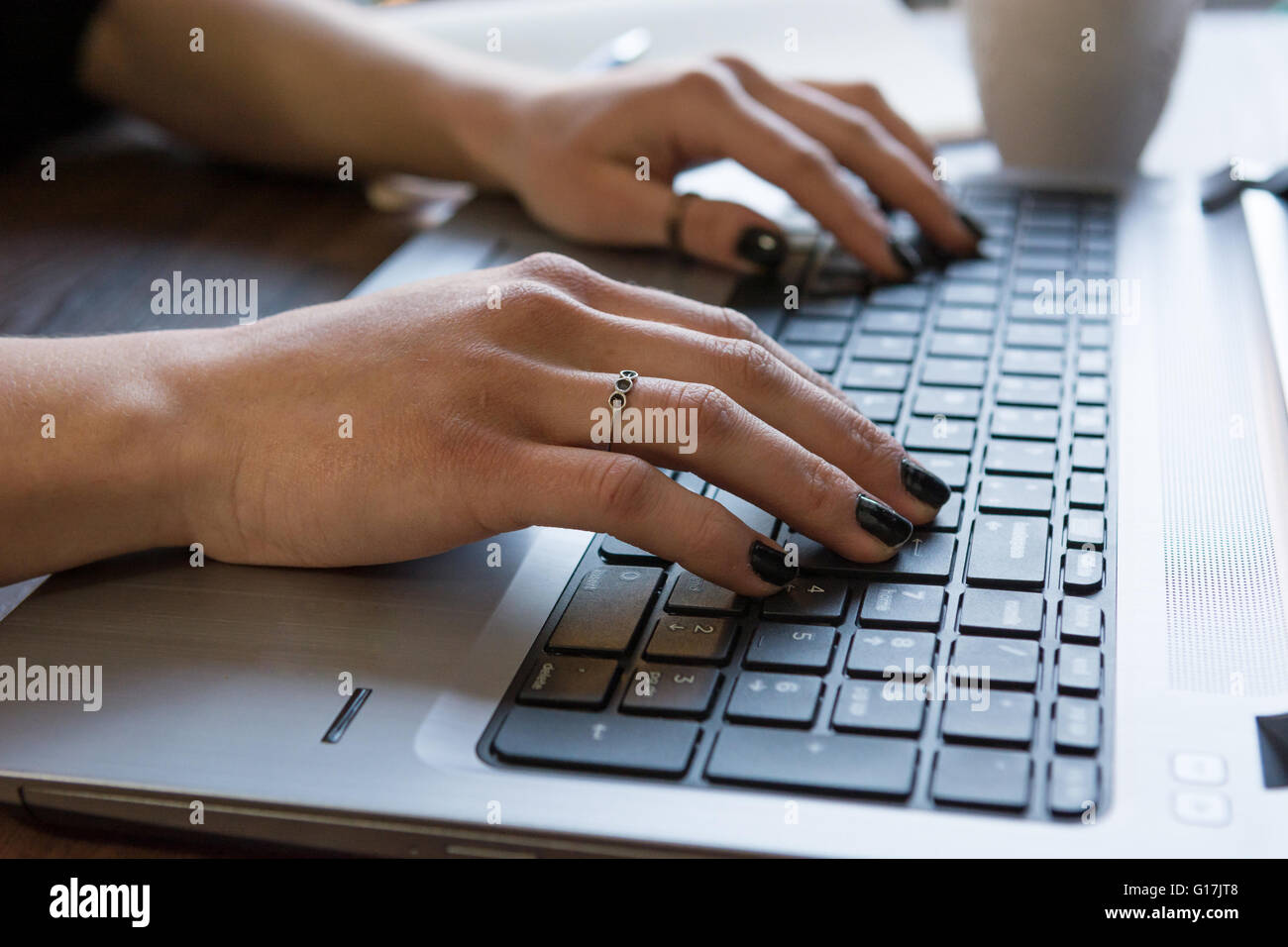 Side view of woman's hands writing on laptop Stock Photo - Alamy