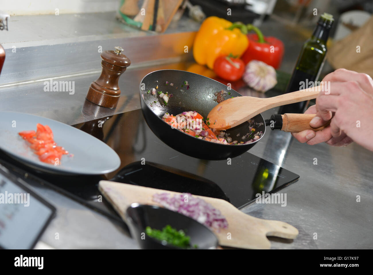 Chef in restaurant kitchen at stove with pan on food Stock Photo - Alamy