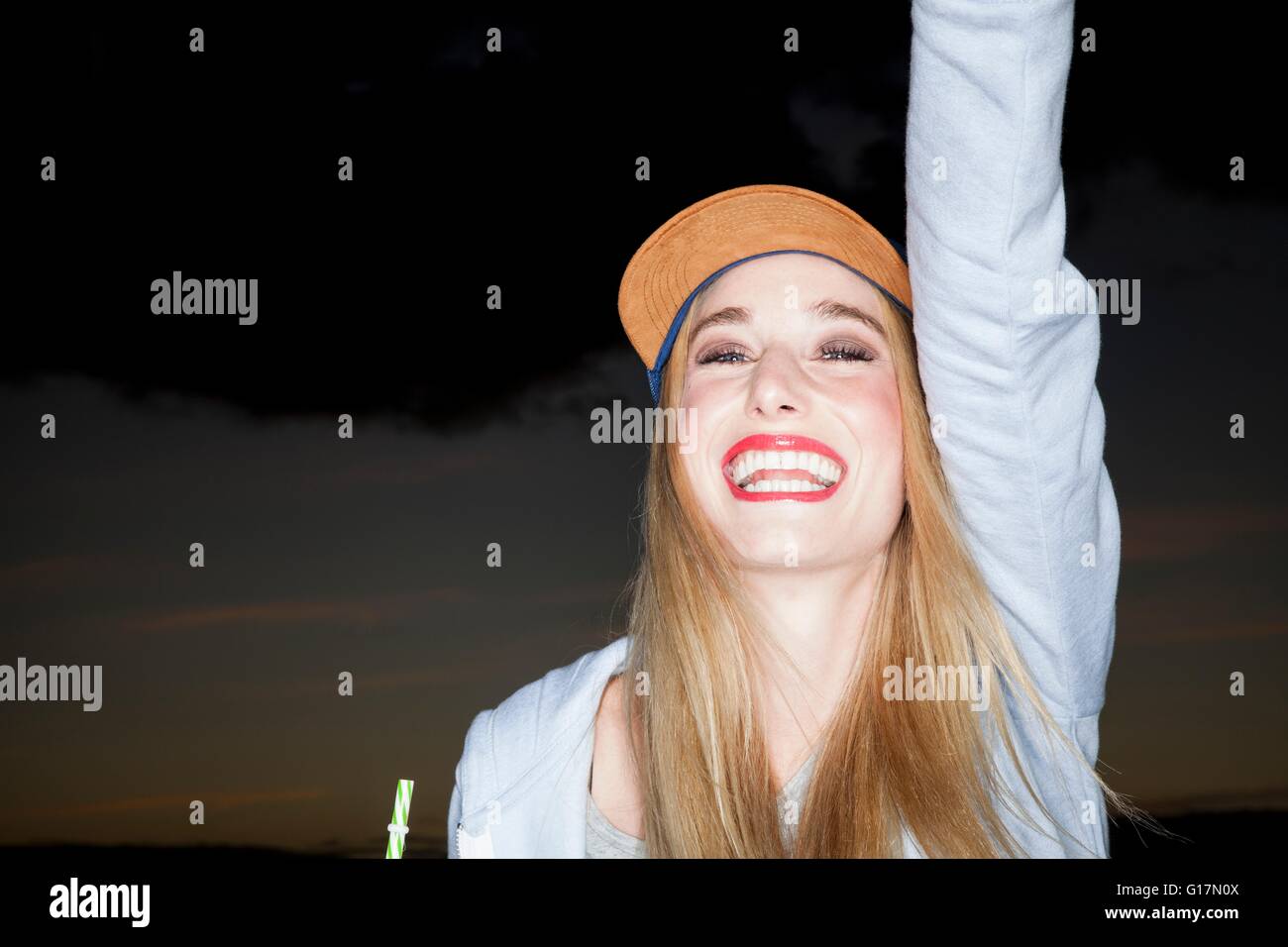 Young woman wearing baseball cap arm raised looking away smiling Stock ...