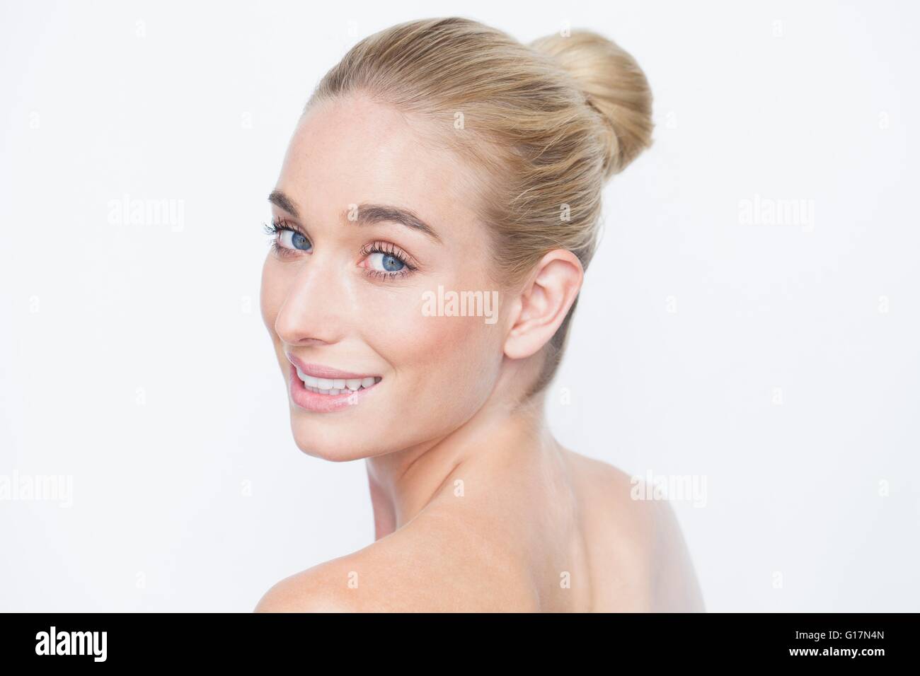 Rear view of woman with hair bun looking over bare shoulder at camera ...