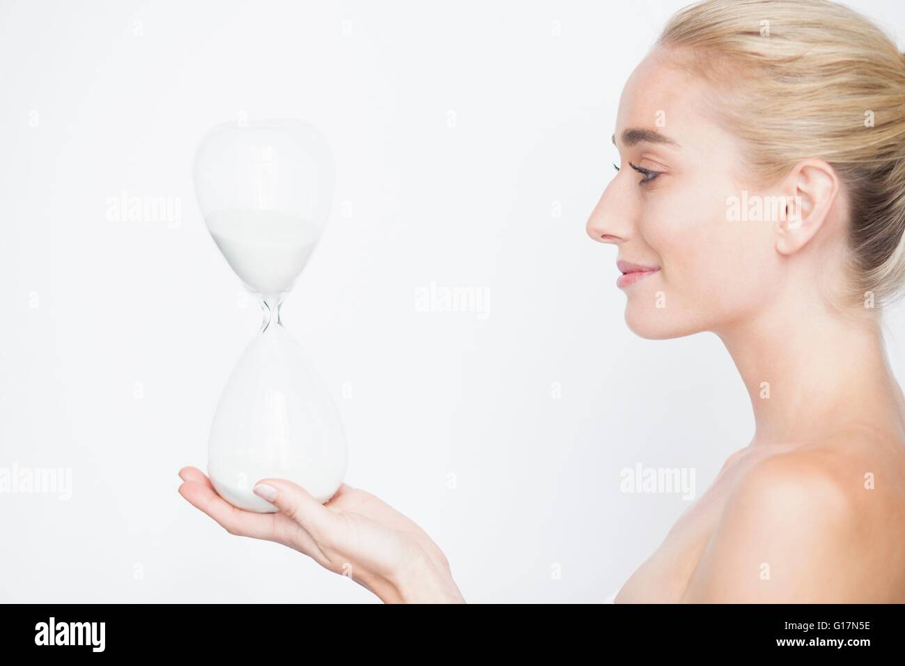 Side view of bare shouldered woman holding hourglass smiling Stock ...