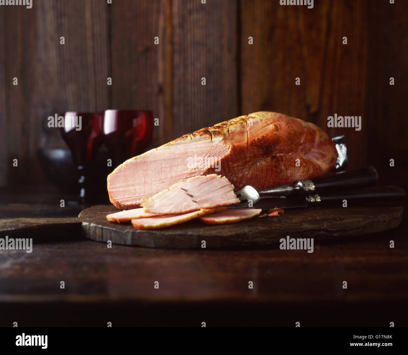 Whole cooked ham, partly sliced, on wooden chopping board Stock Photo ...