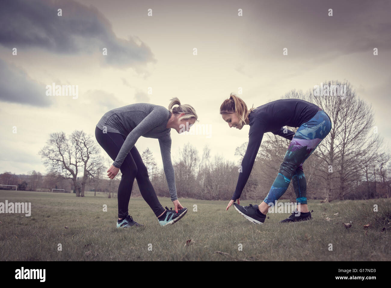 Side view of women in field bending forward touching toes Stock Photo ...
