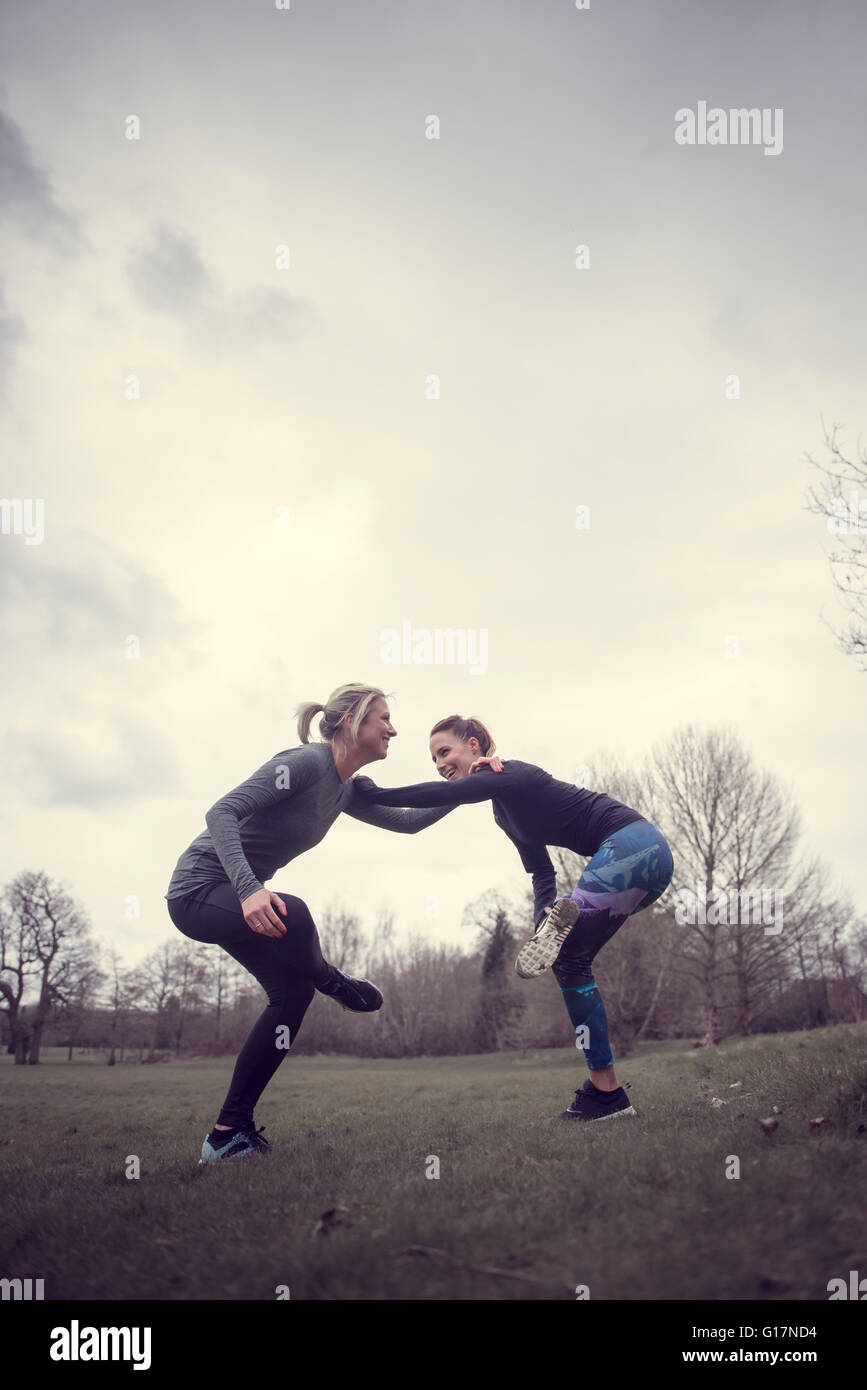 Women in field hands on each other shoulders, balancing on one leg ...