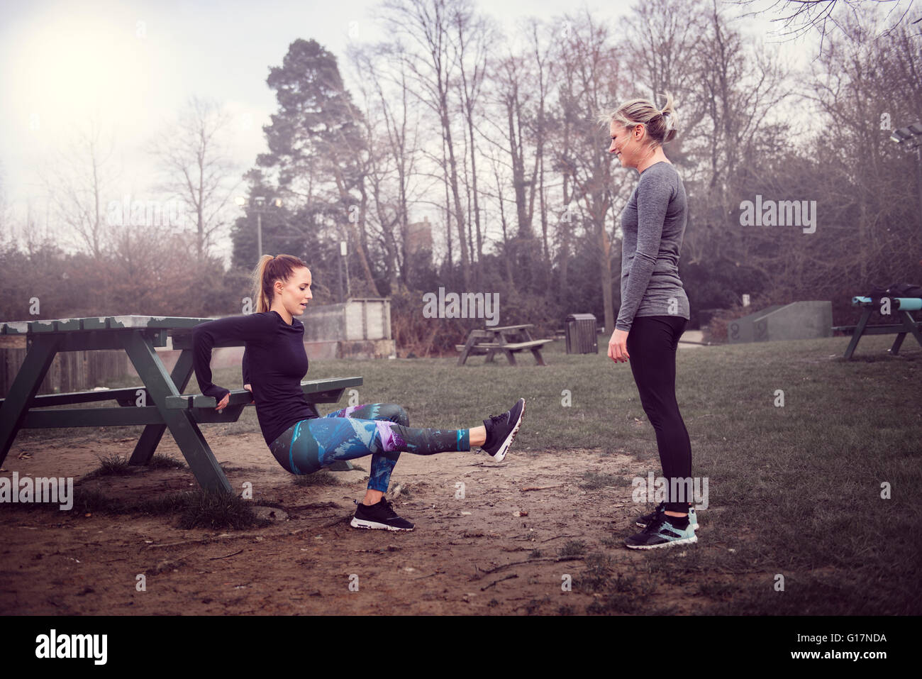 Women doing reverse push up on picnic bench Stock Photo - Alamy
