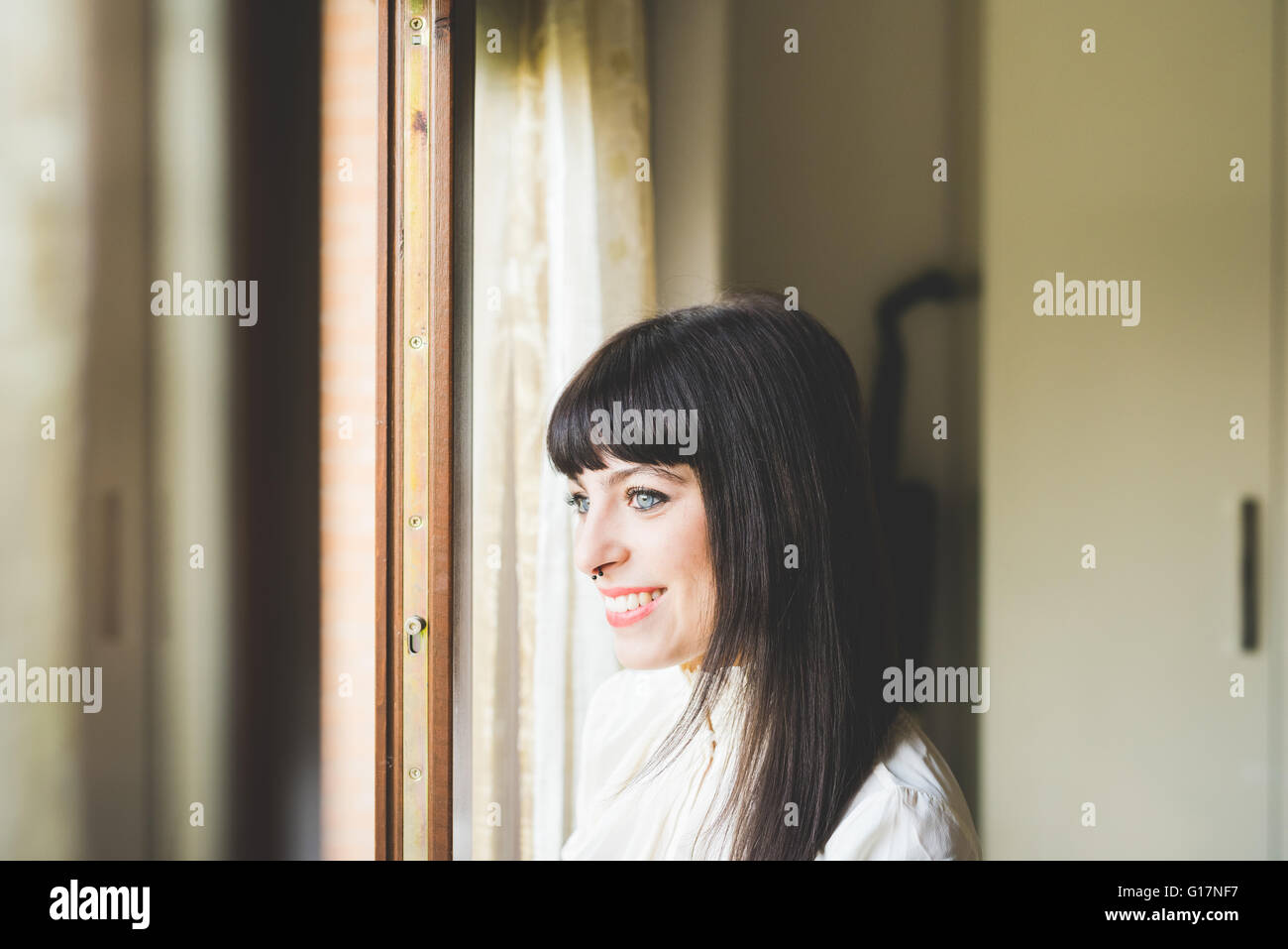 Young woman looking out of window Stock Photo - Alamy
