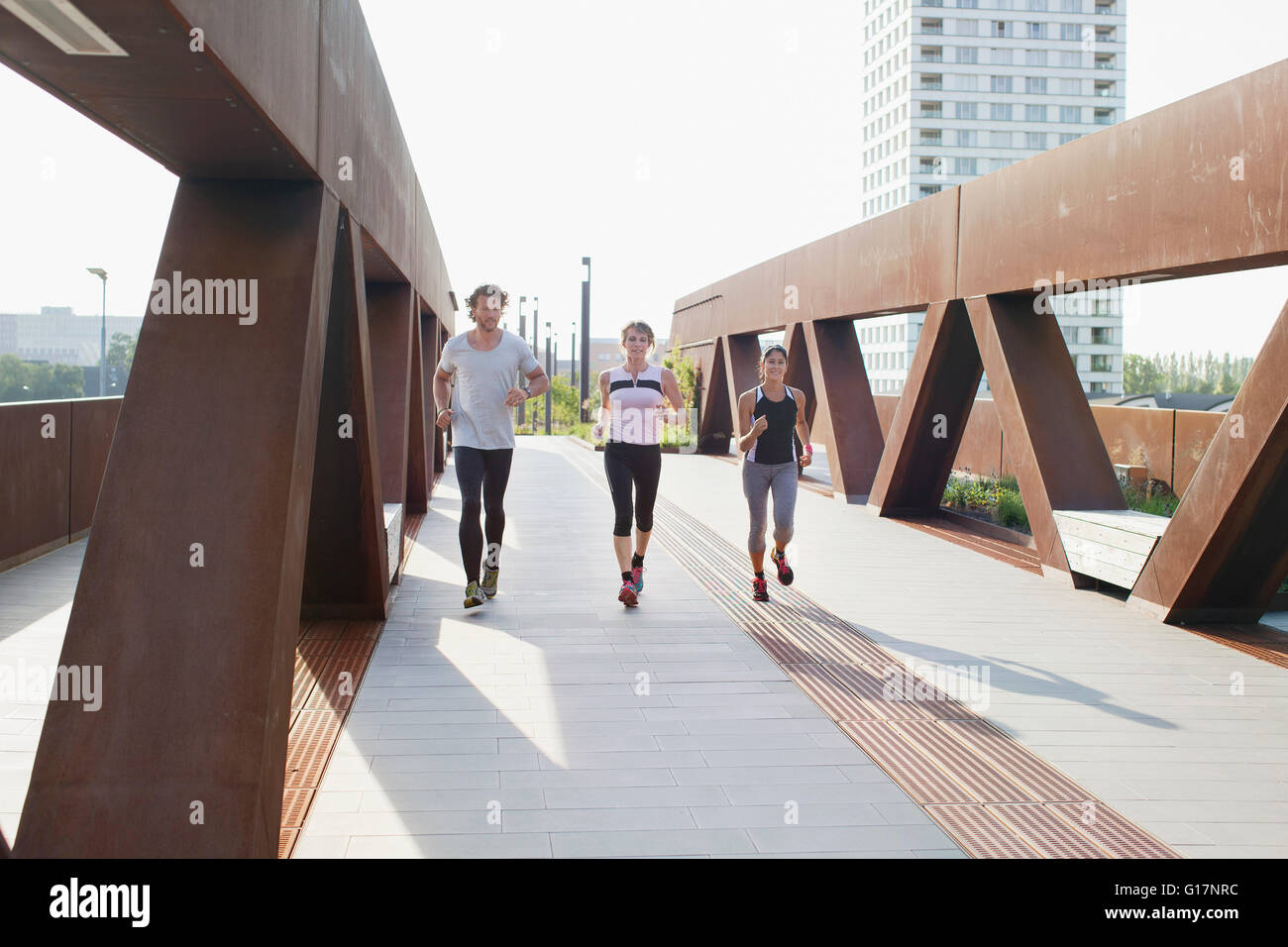 Male and female runners running on urban footbridge Stock Photo - Alamy