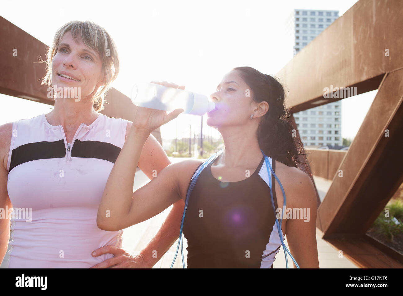 Two women taking a water break from training on urban footbridge Stock ...