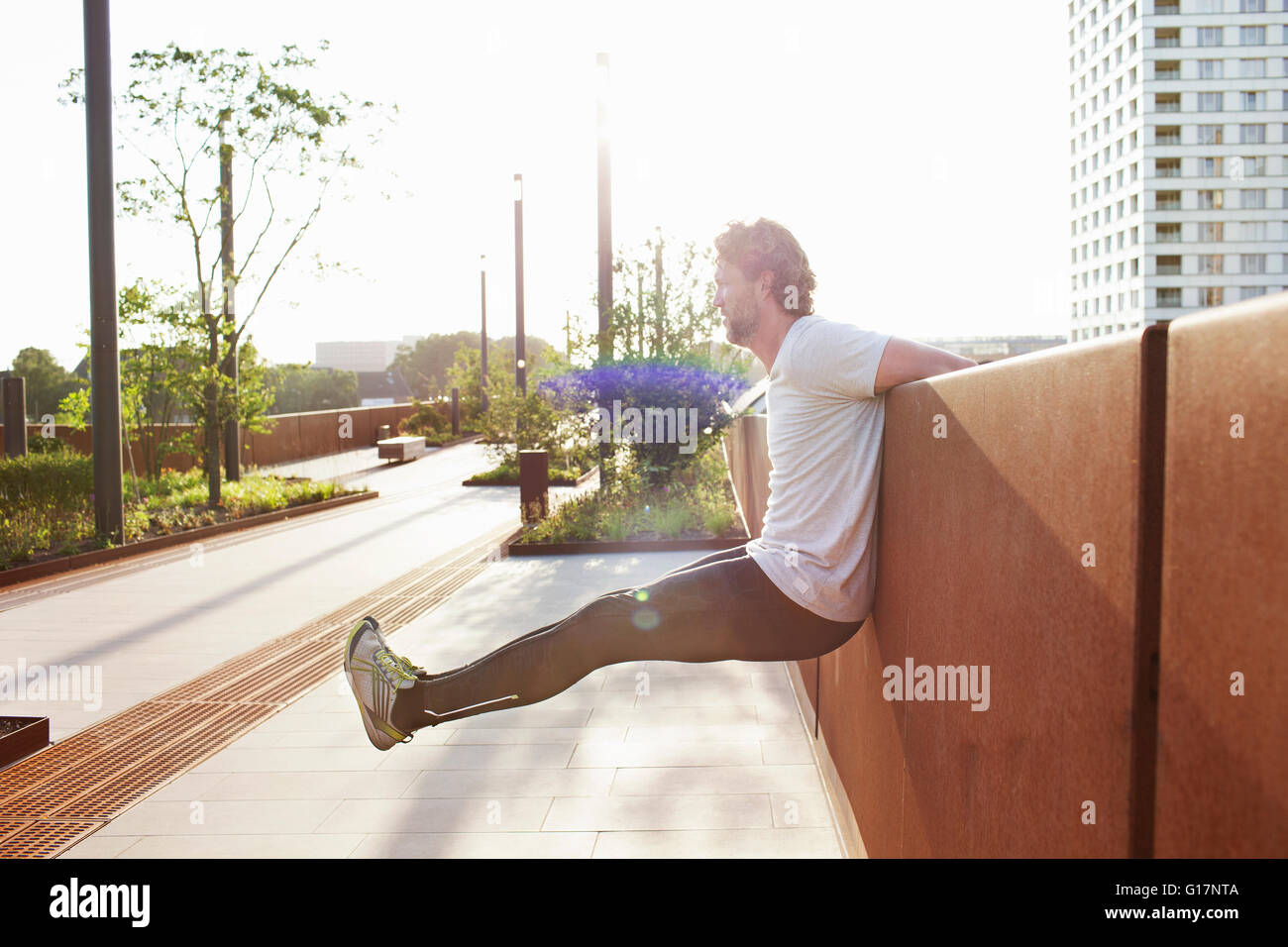 Man training raising his legs on urban footbridge Stock Photo - Alamy