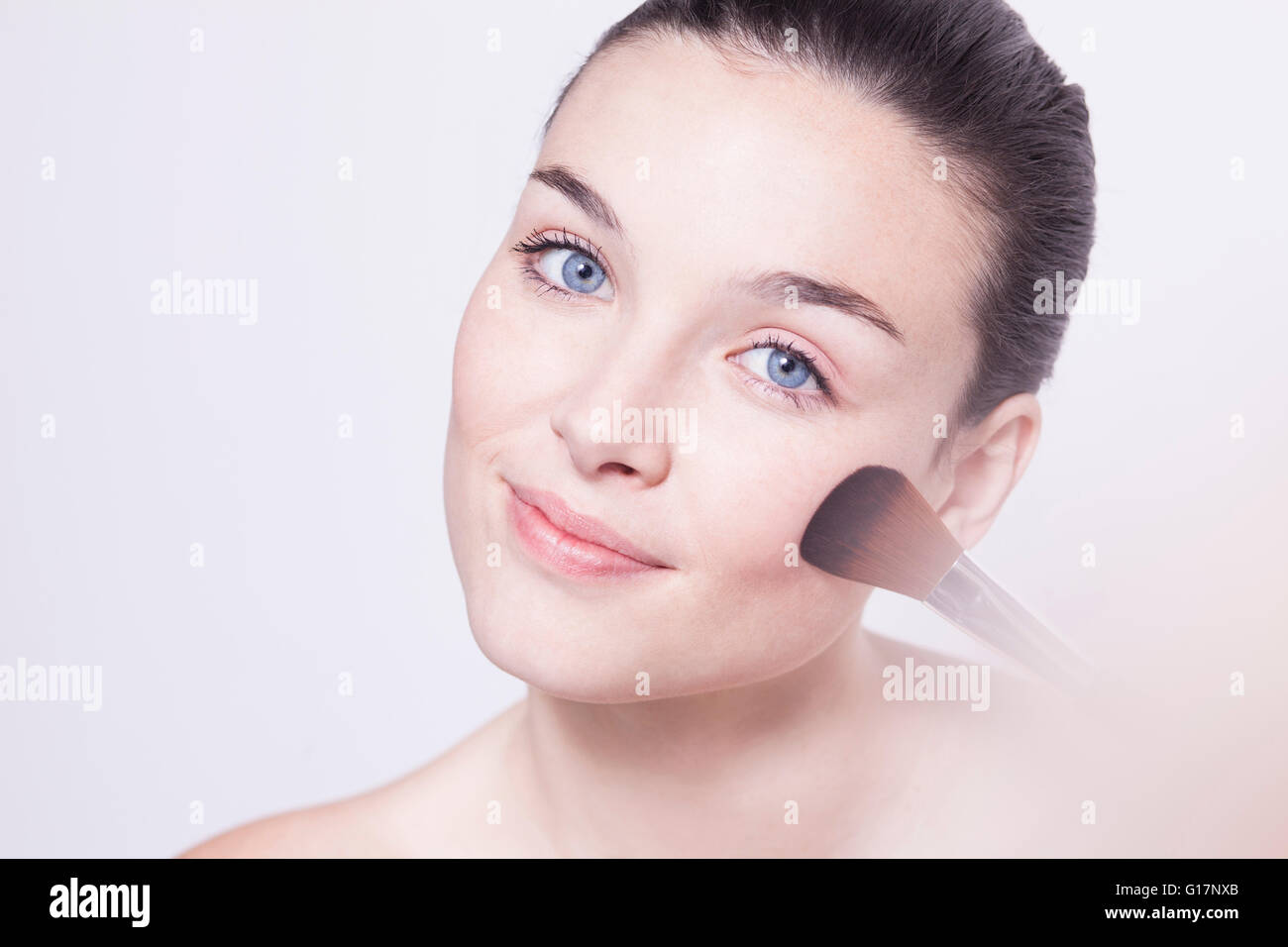 Portrait of beautiful young woman applying blusher Stock Photo - Alamy