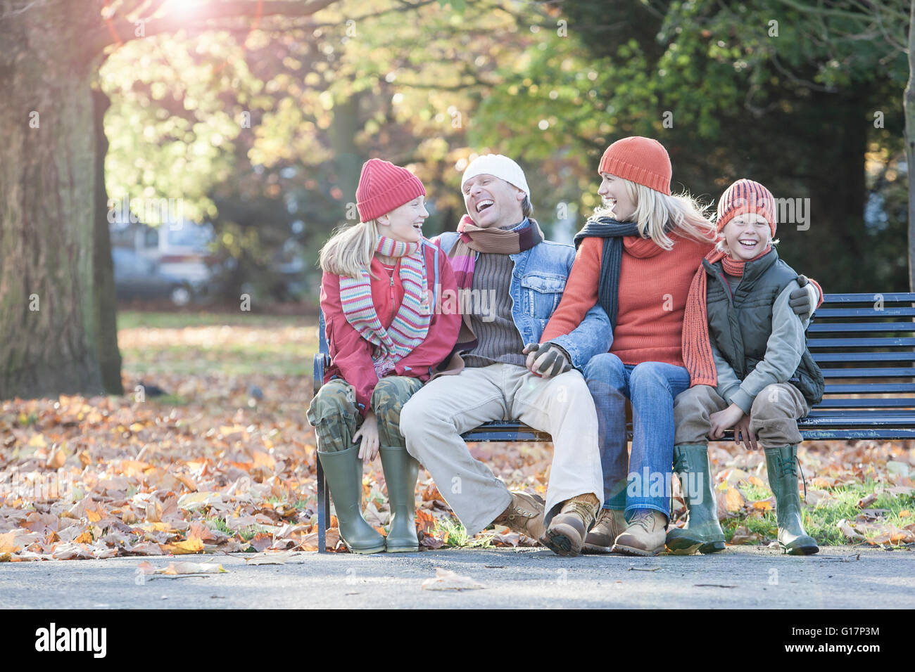 Family sitting together on park bench, laughing Stock Photo - Alamy