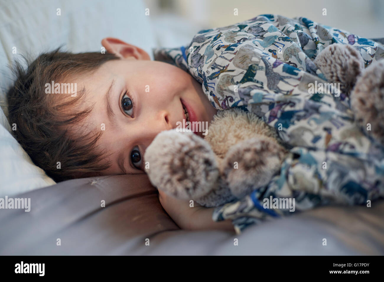 Boy in pyjamas hugging soft toy in bed Stock Photo - Alamy
