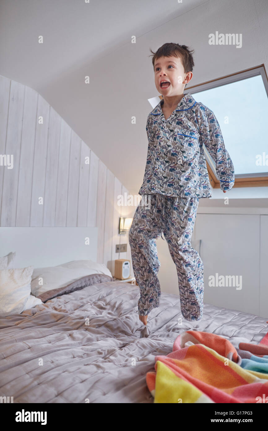 Boy in pyjamas jumping on bed in loft room Stock Photo - Alamy