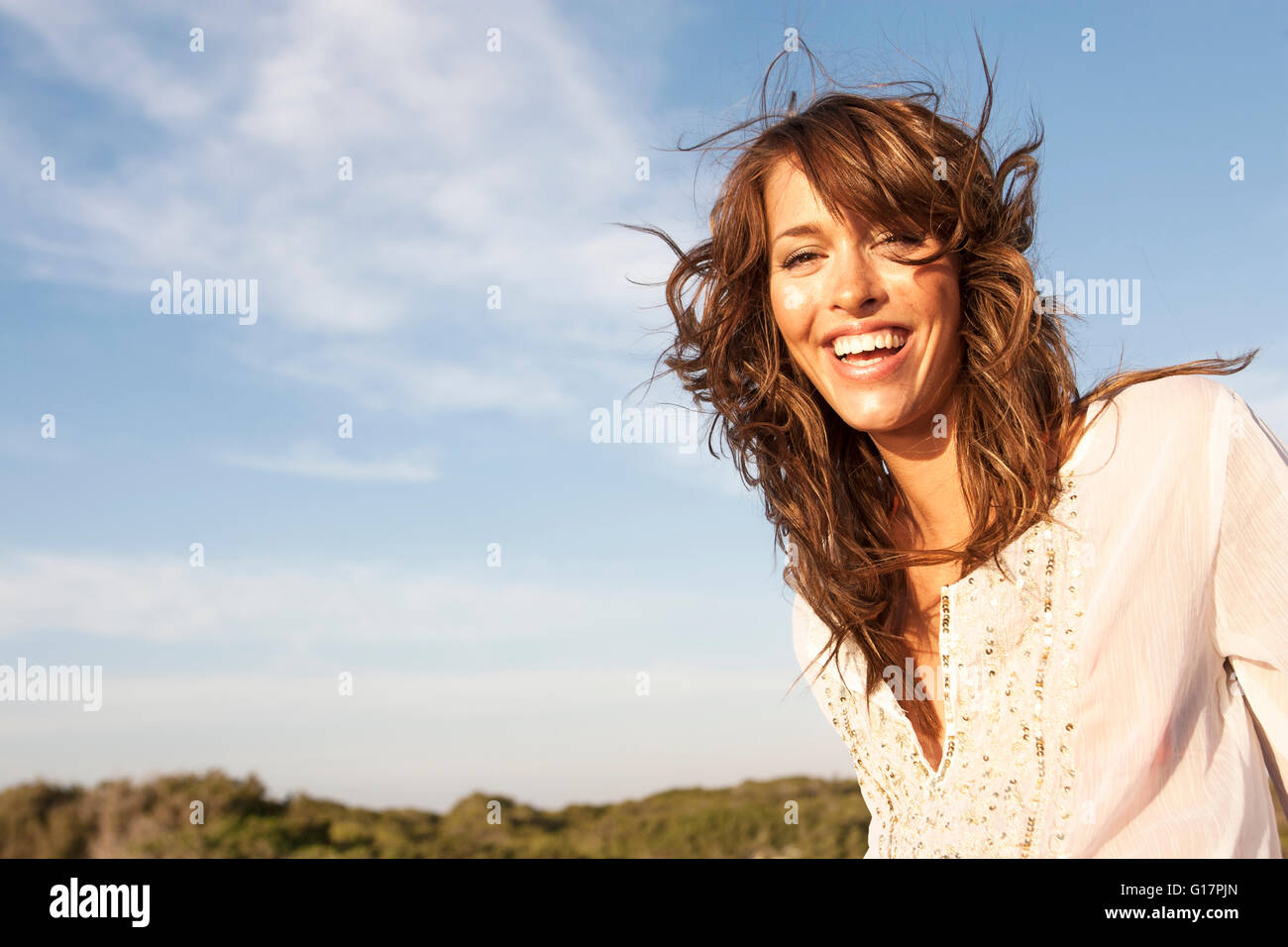Portrait of young woman with flyaway hair against blue sky Stock Photo ...