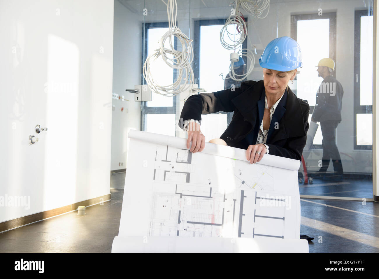 Businesswoman rolling blueprint in new office Stock Photo - Alamy
