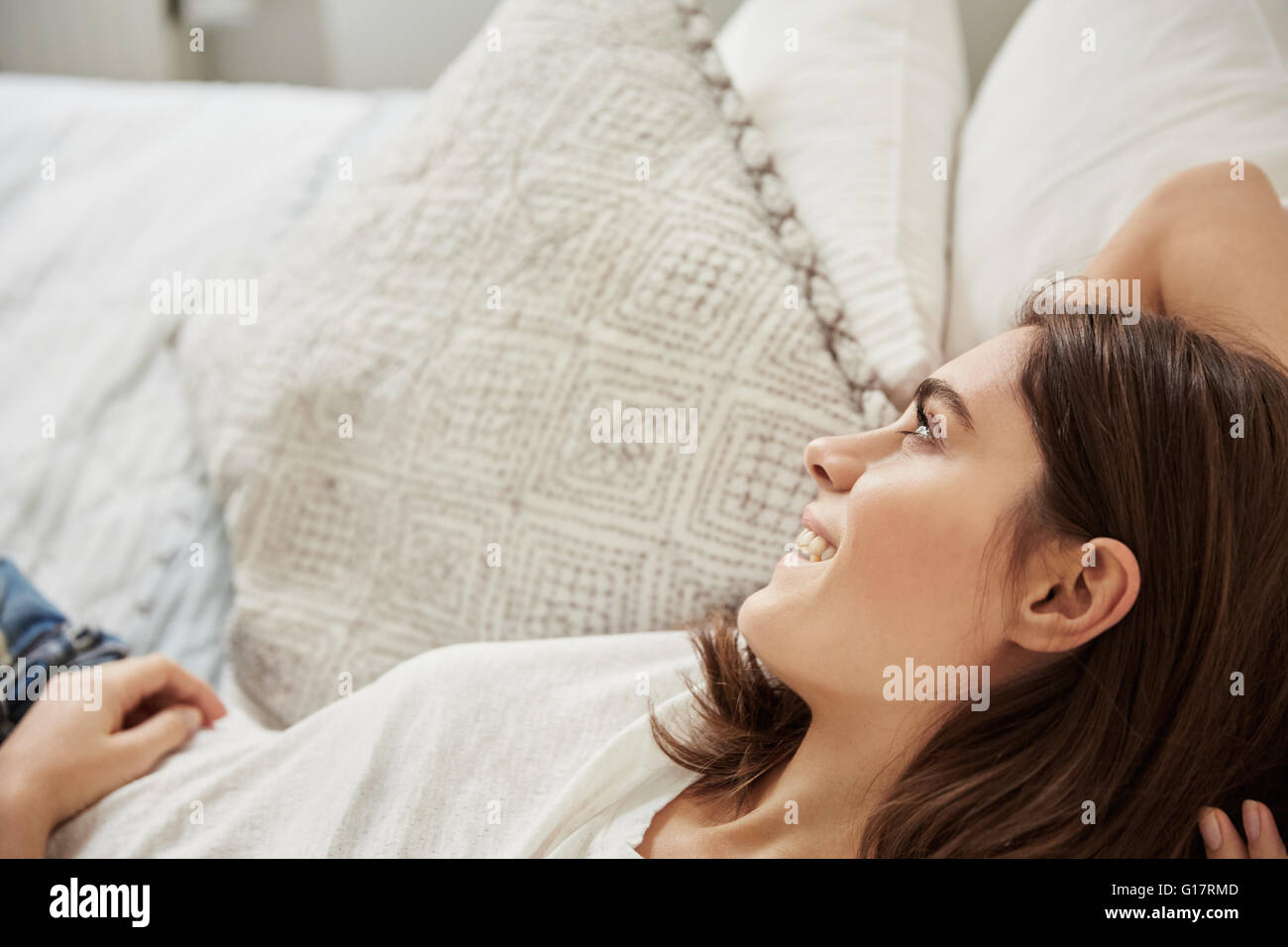 Beautiful young woman lying back on bed Stock Photo - Alamy