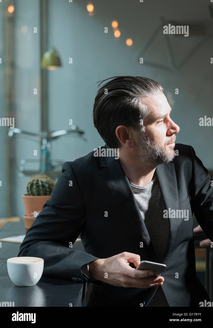 Cool businessman looking over shoulder from cafe window seat Stock ...