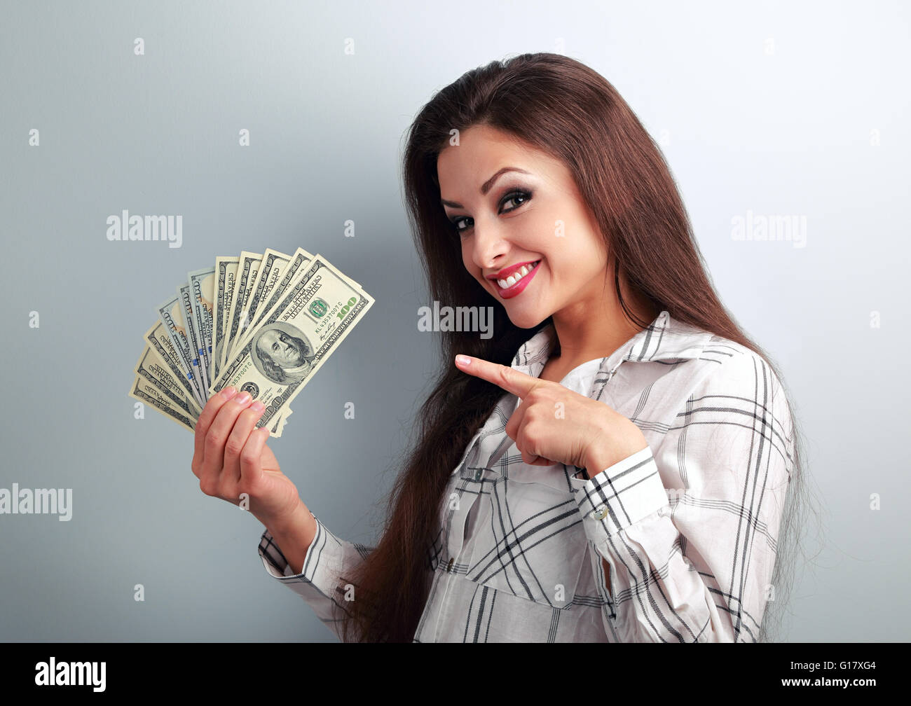 Happy successful young pretty woman showing the finger on dollars in ...
